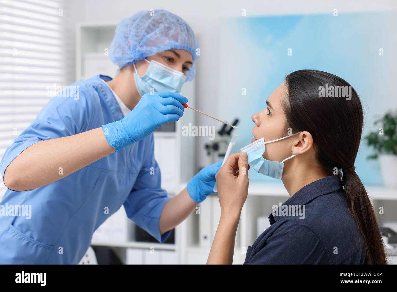 Laboratory testing. Doctor taking sample from patient's mouth with ...