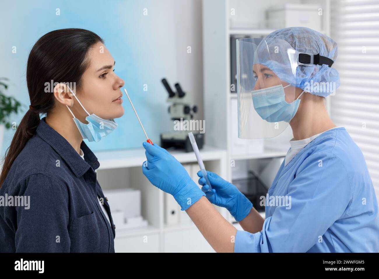 Laboratory testing. Doctor in uniform taking sample from patient's nose ...