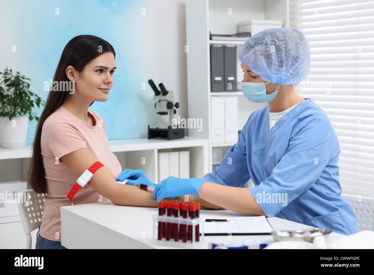 Laboratory testing. Doctor taking blood sample from patient at white ...