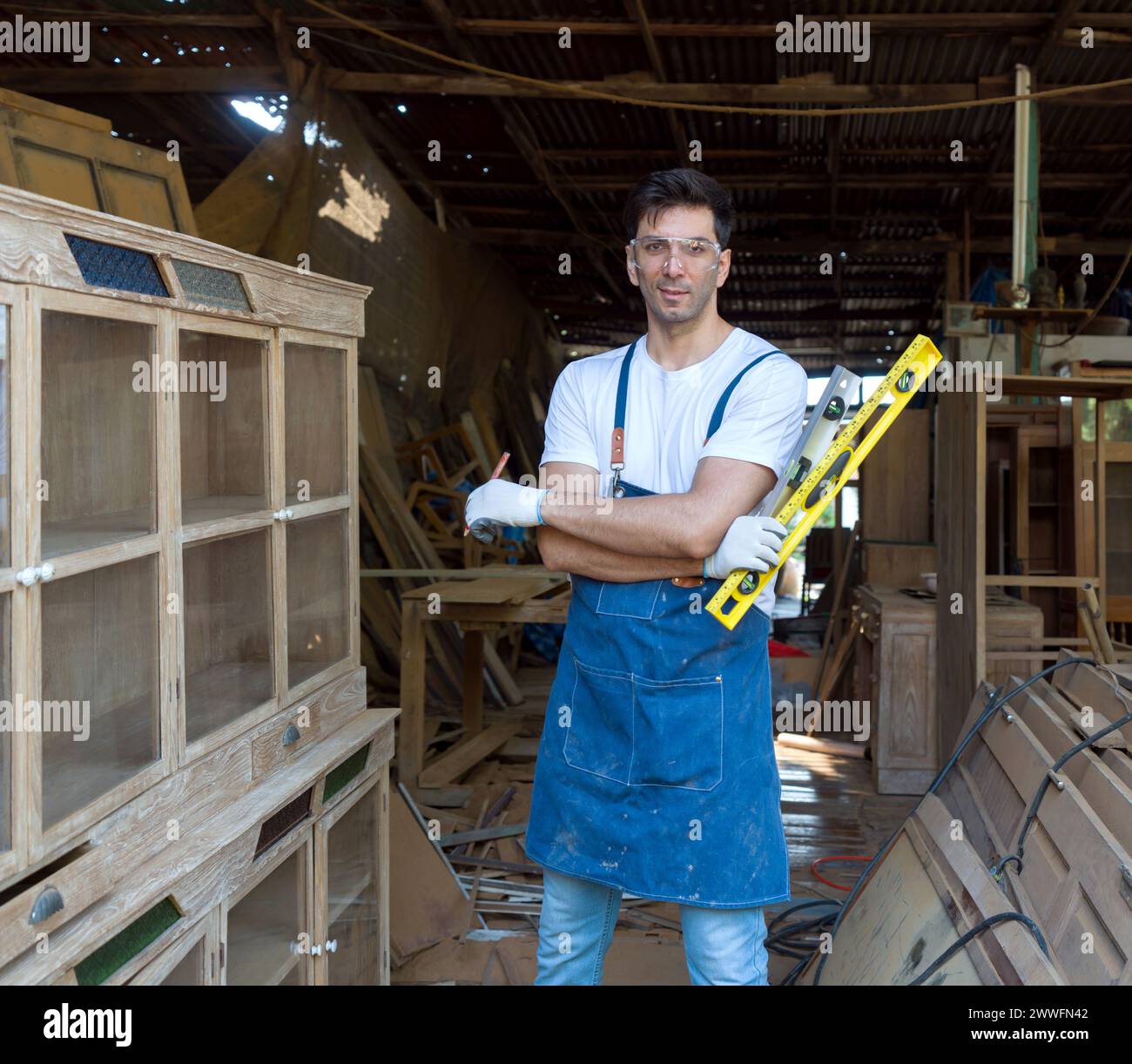 Young carpenter or woodworker with safety glasses, work apron, and ...