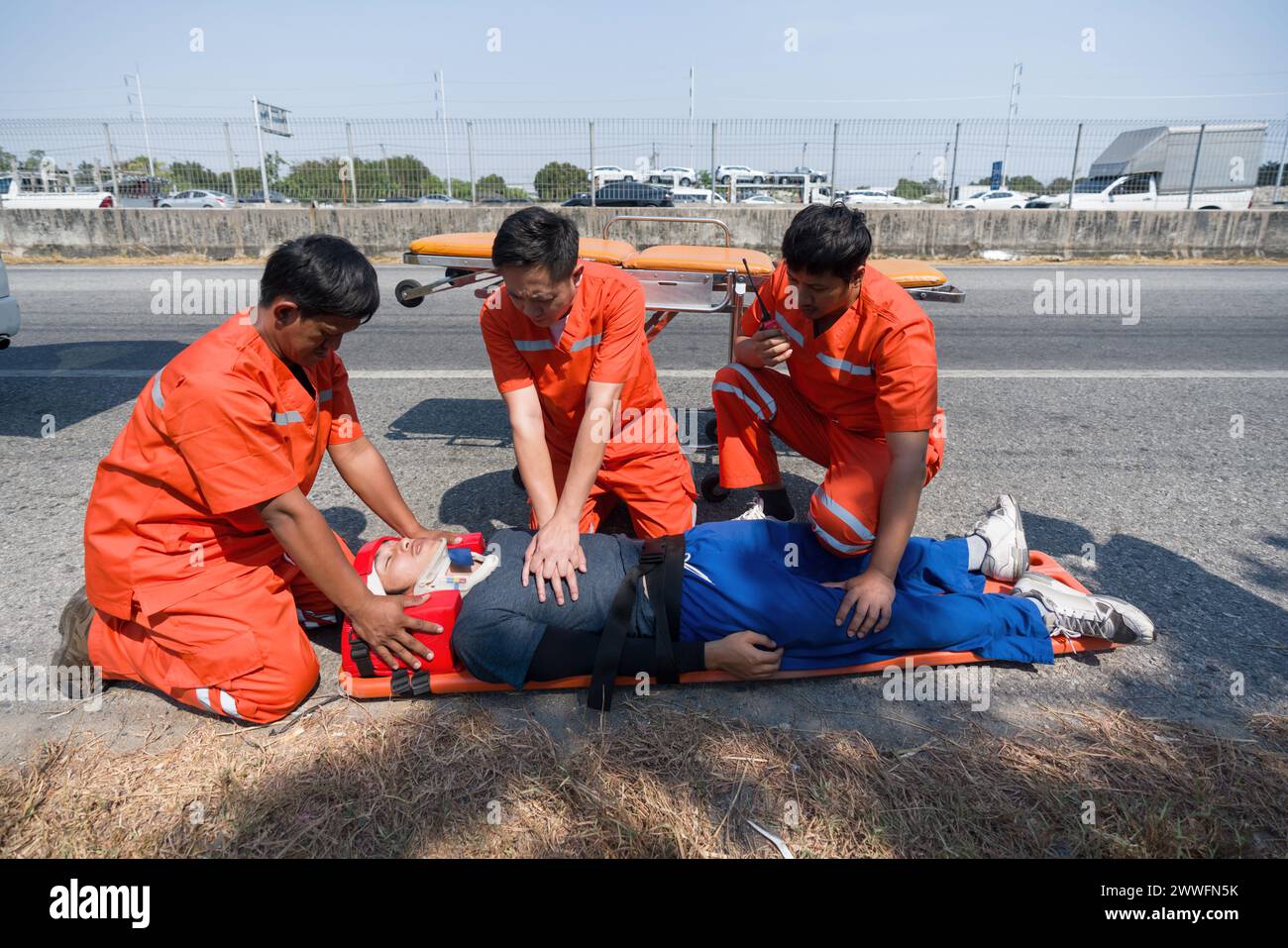A man in head immobilizer tool lying on stretcher long spinal board ...