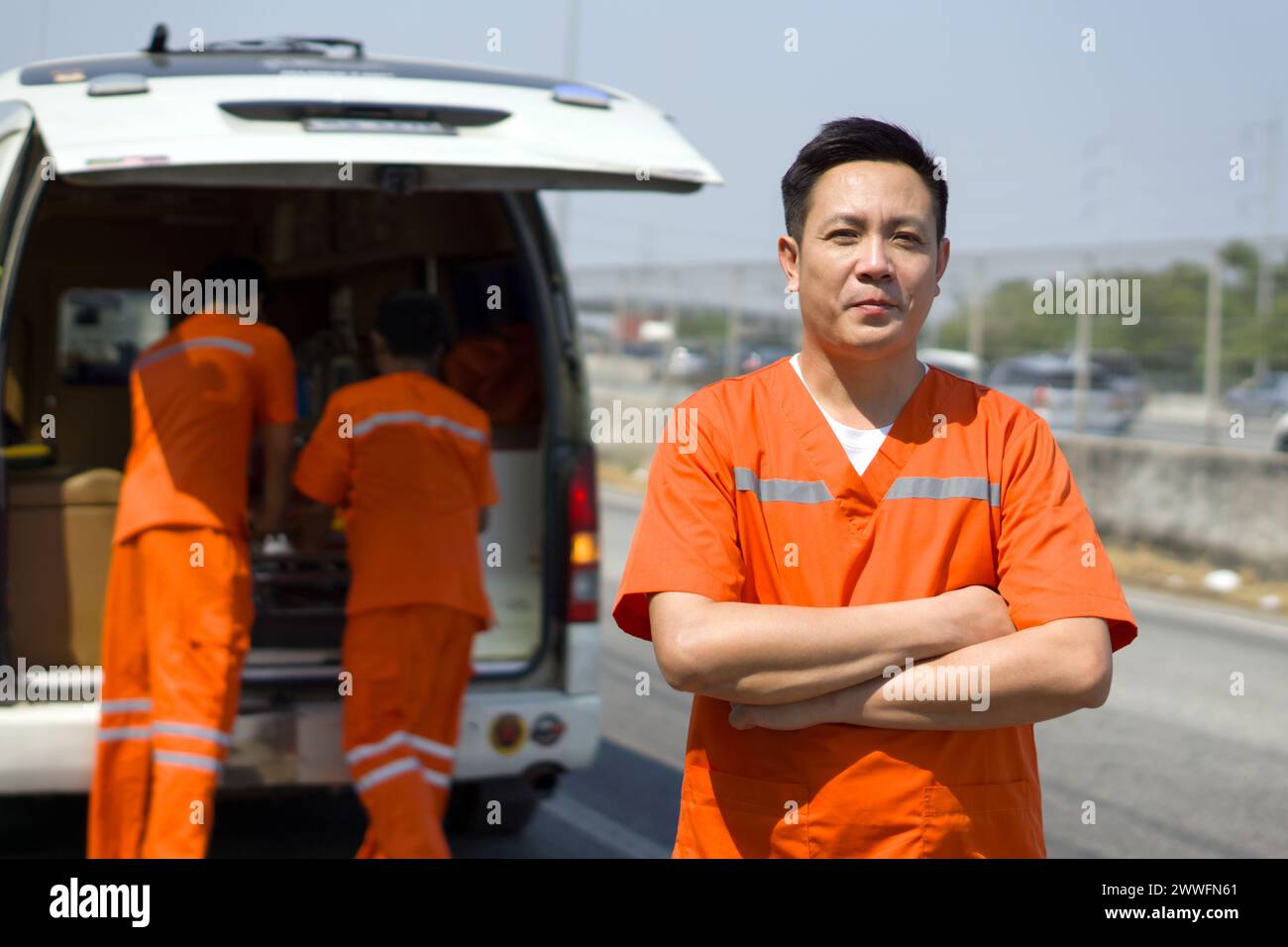 Asian rescue staff in orange uniform stand in front of an ambulance ...