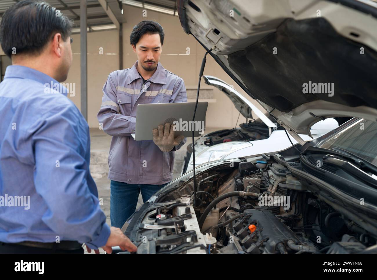 Car owner and mechanic engaged in a vehicle maintenance or diagnostic ...