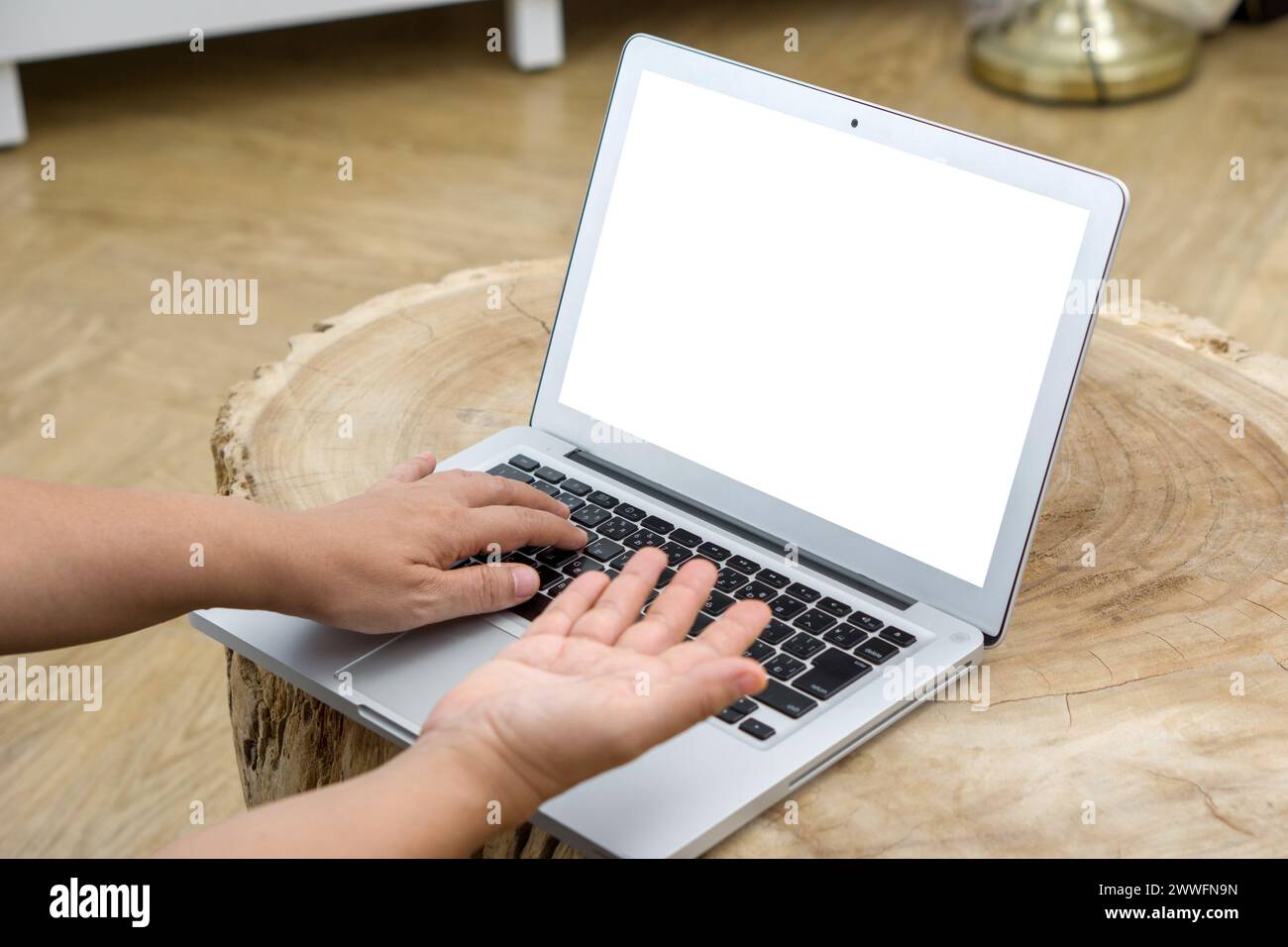 An individual engrossed in work on a white screen laptop. The laptop is ...