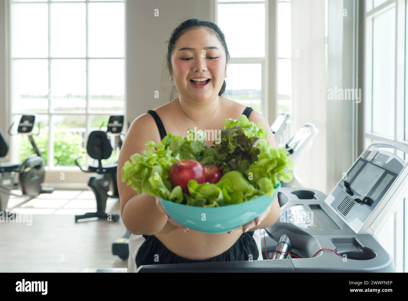 A plus-sized lady standing on a treadmill, maintaining her health by ...