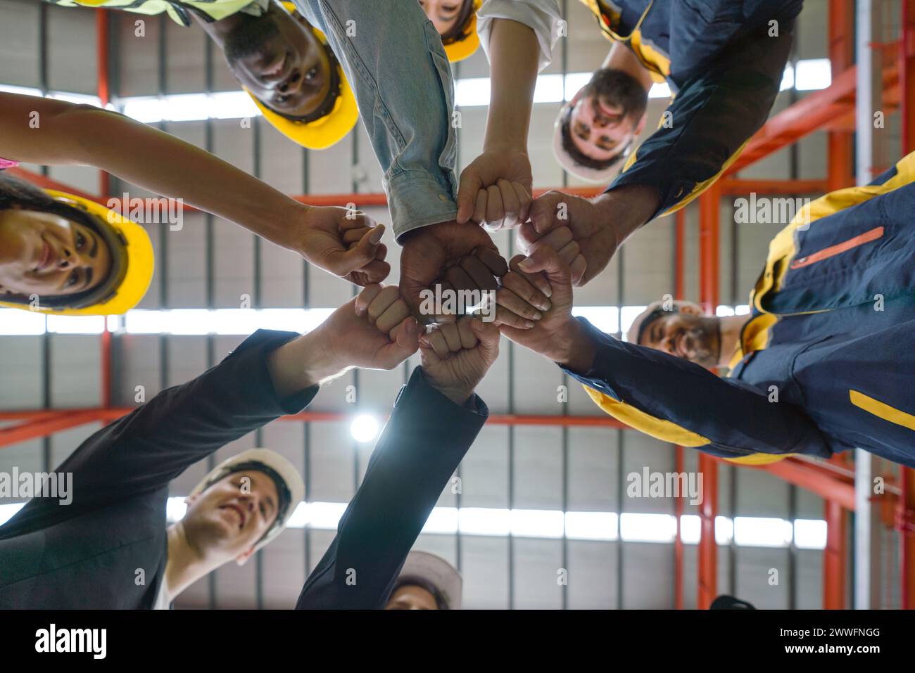 Group of male and female factory labor bump their fist together after ...