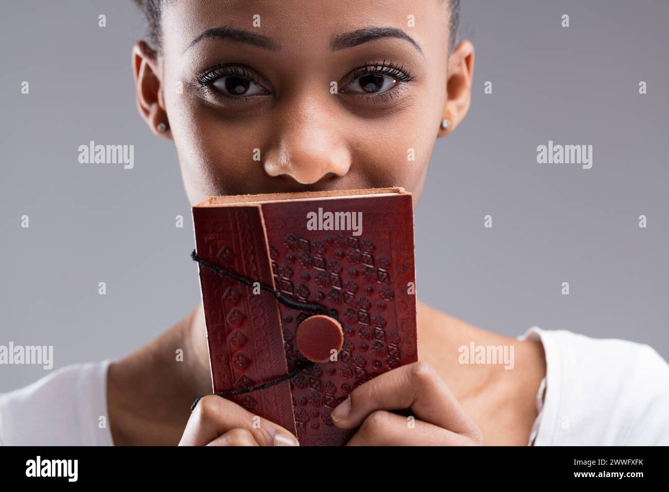 Curious eyes peek over an ornate book, suggesting a world of stories ...