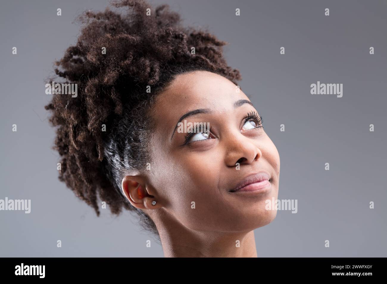 Her eyes lifted, the woman's face radiates optimism, framed by her ...