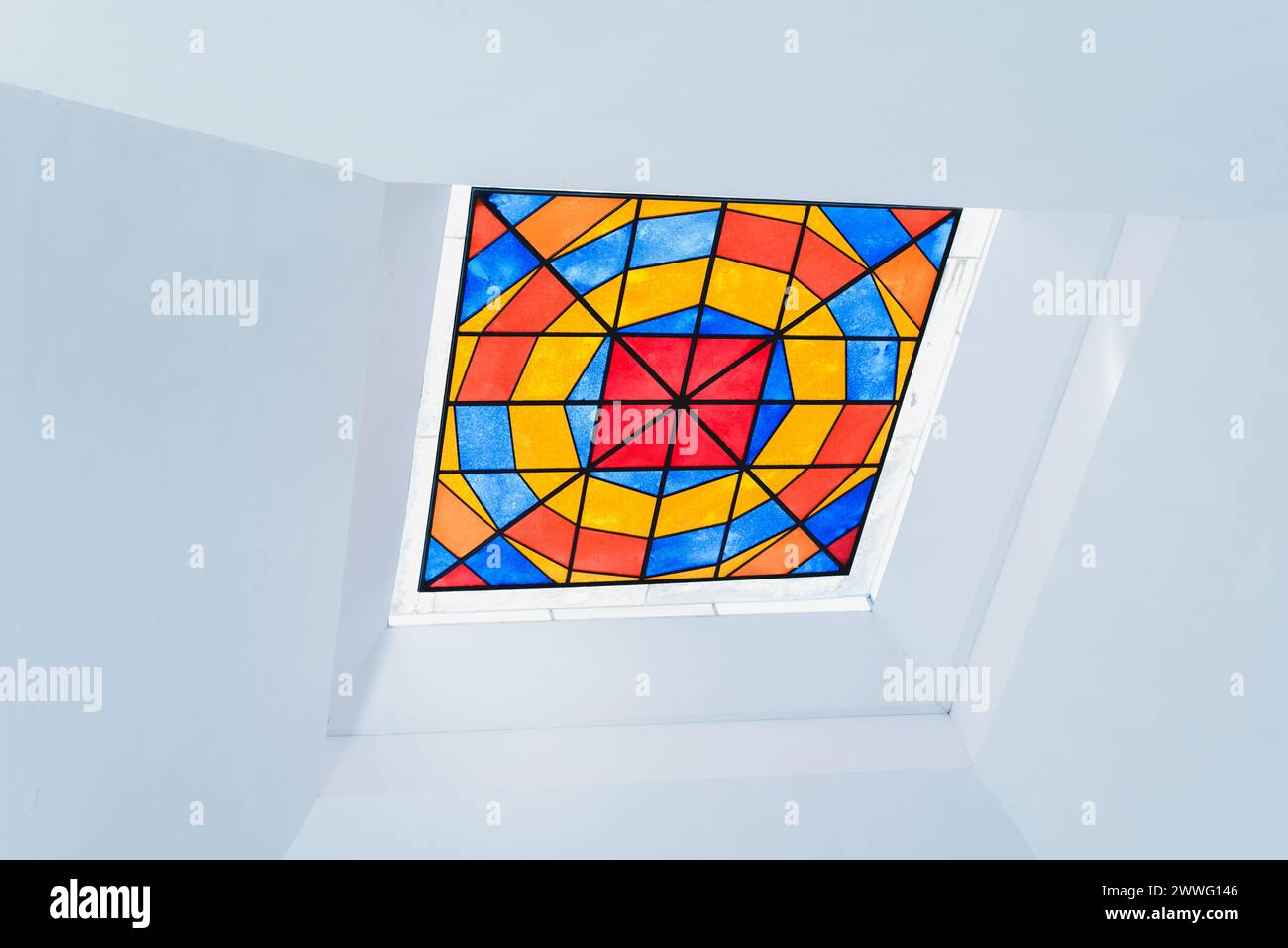 Colorful square stained glass window in a white painted ceiling. View ...