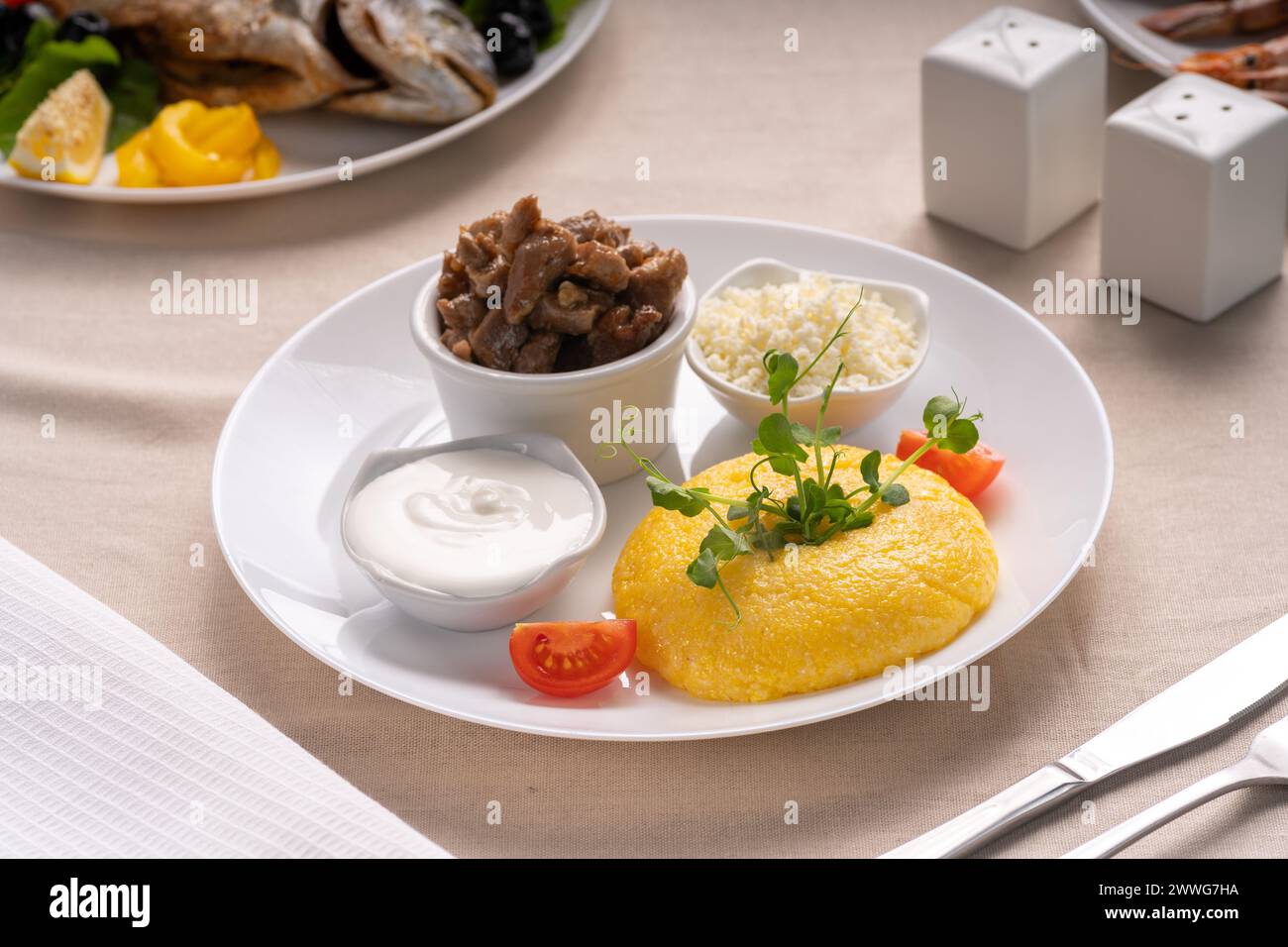 Delicious polenta with cheese, stew meat and sour cream on white plate ...