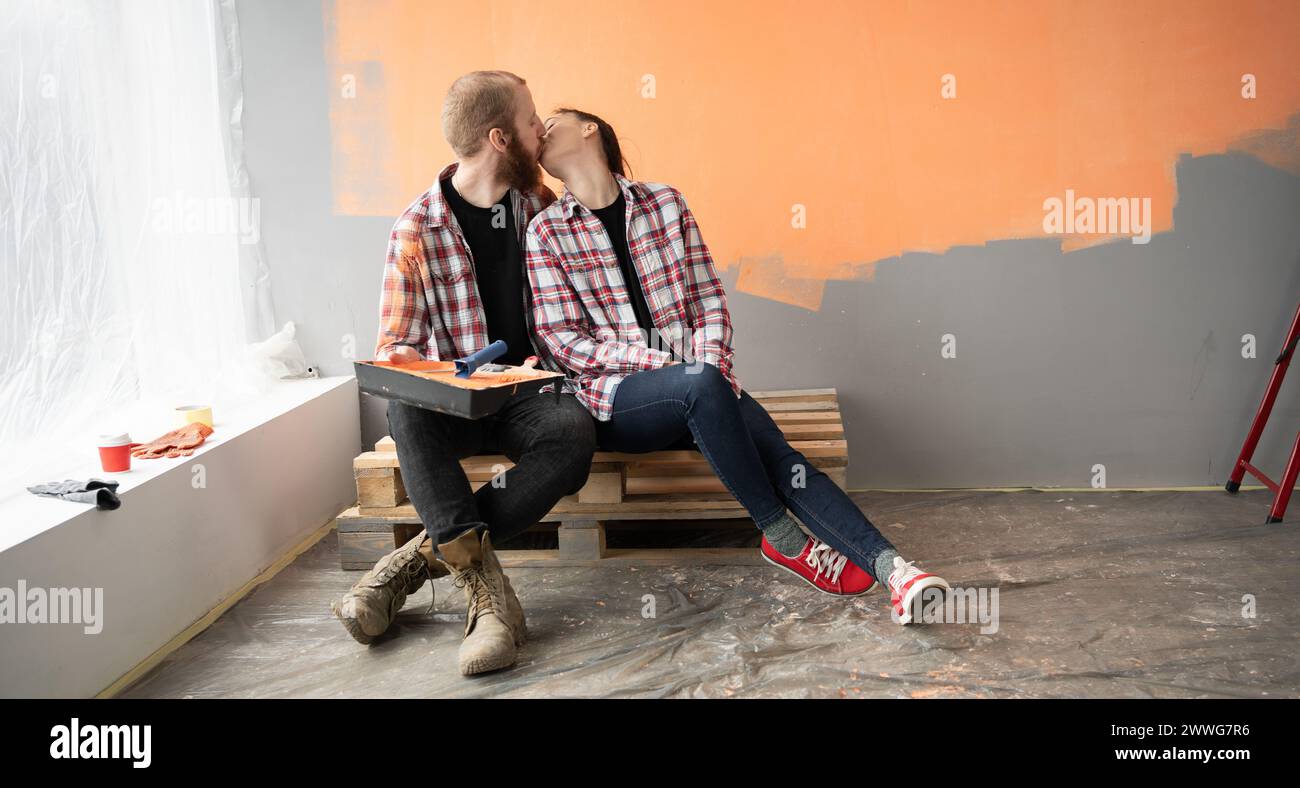 Cheerful young couple renovation in their new apartment, kissing while ...