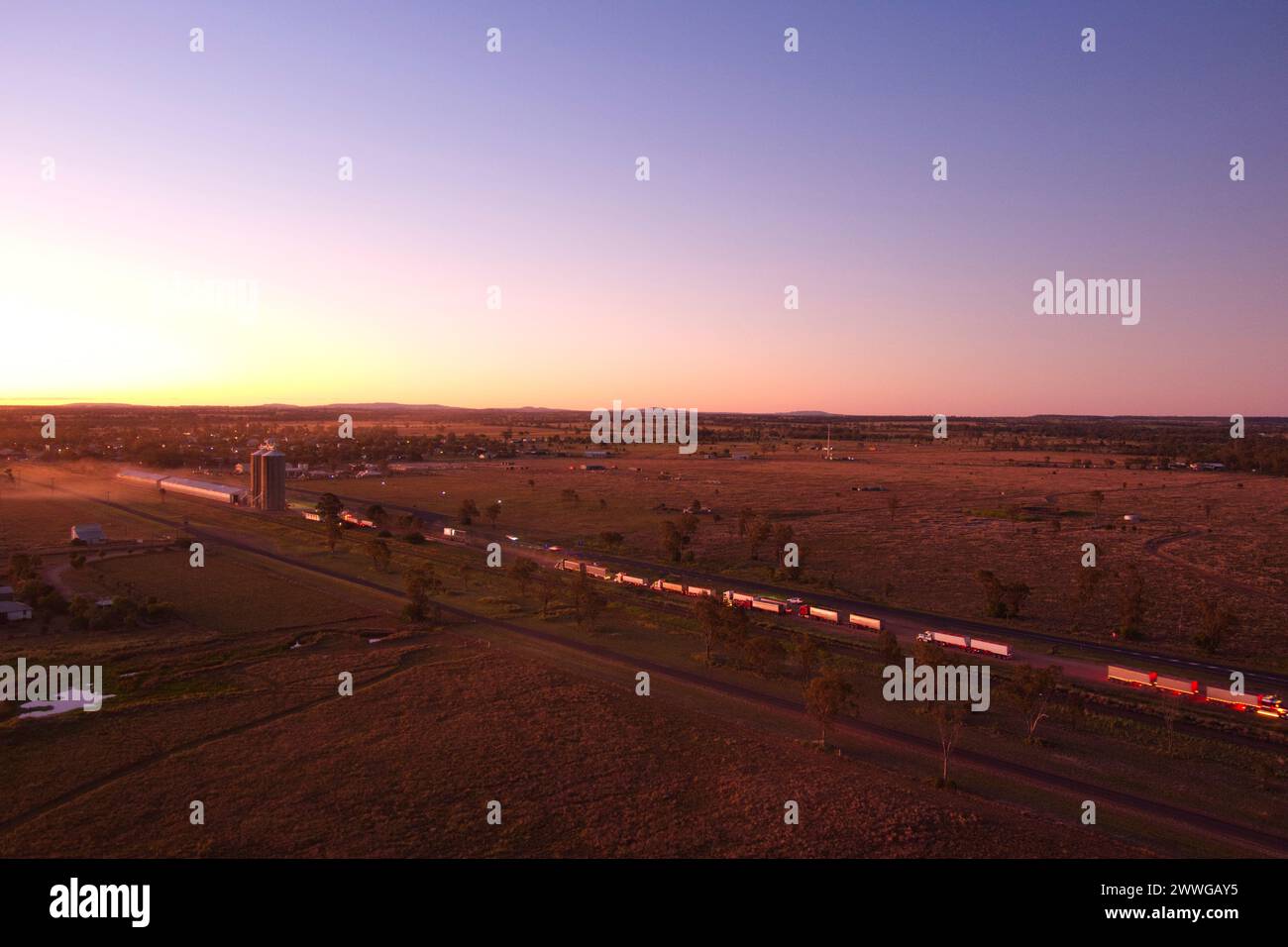 Aerial of sunset over trucks delivering wheat grain to the silo's ...