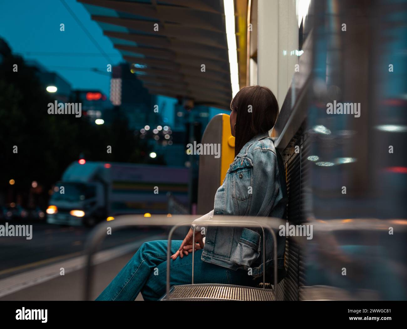 A woman patiently waiting for a train at a bus stop in the dark Stock Photo - Alamy