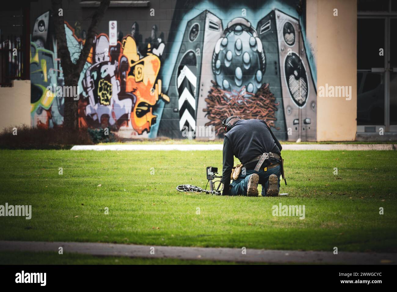 Captured from ground level, a man examines intricate graffiti artwork ...