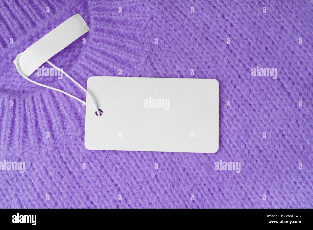 Blank clothing tag and inner label on neck of purple knitted sweater ...