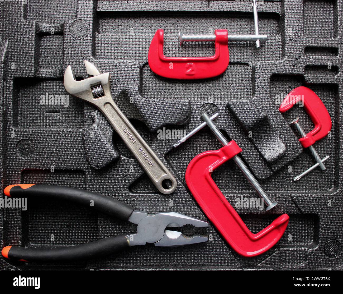Pliers, adjustable wrench and different thread clamps in styrofoam ...
