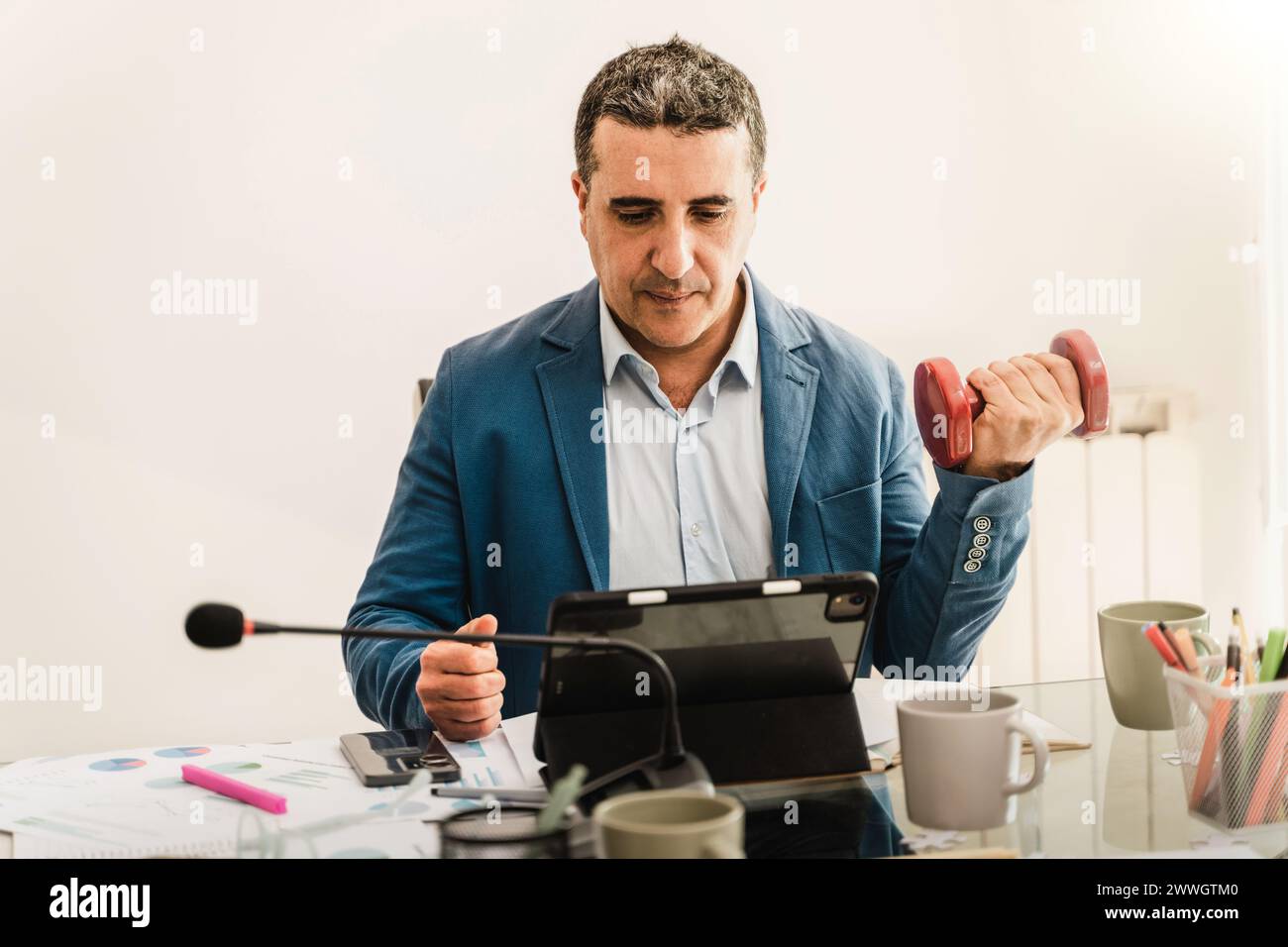 Businessman lifting weights while working - staying fit in office ...