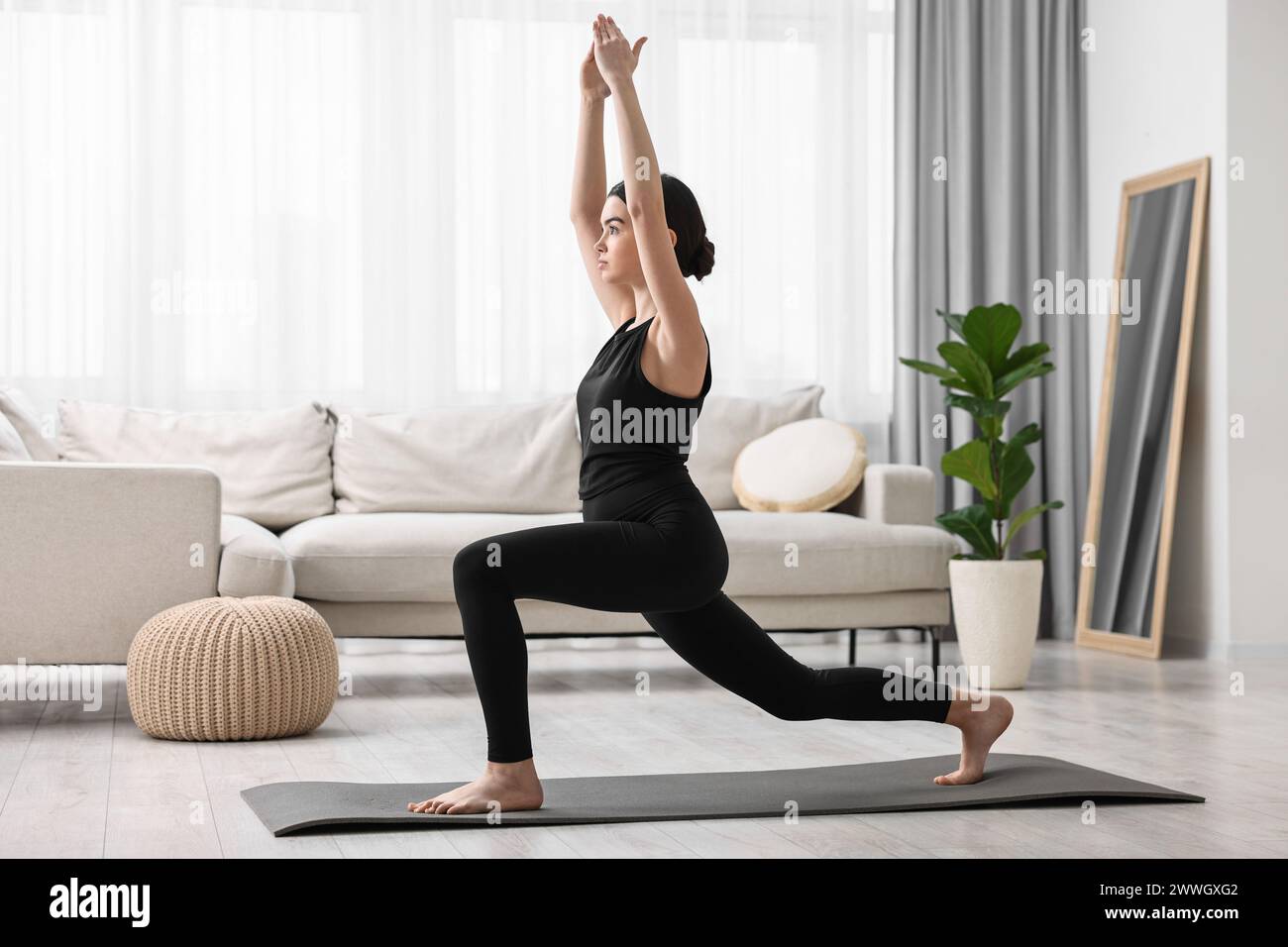 Girl practicing crescent asana on yoga mat at home. High lunge pose ...
