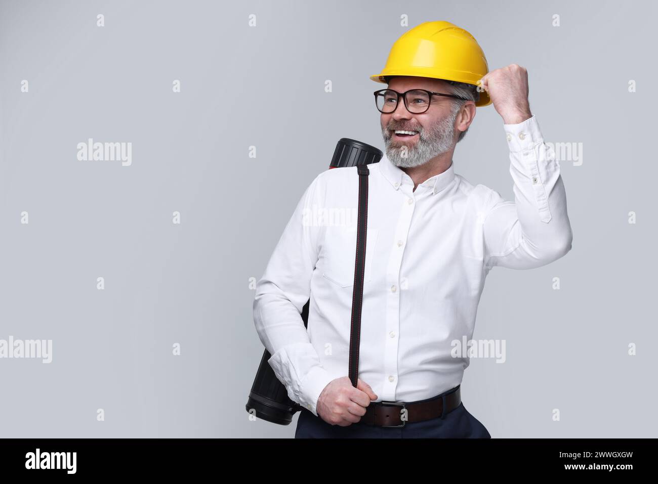 Architect in hard hat with drawing tube on grey background Stock Photo ...