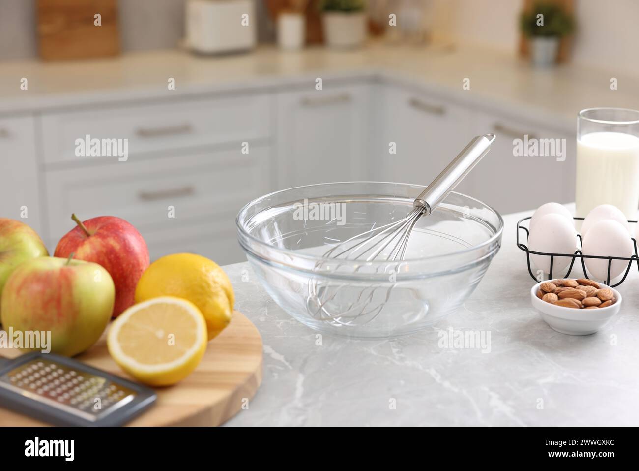Metal whisk, bowl, grater and different products on gray marble table ...