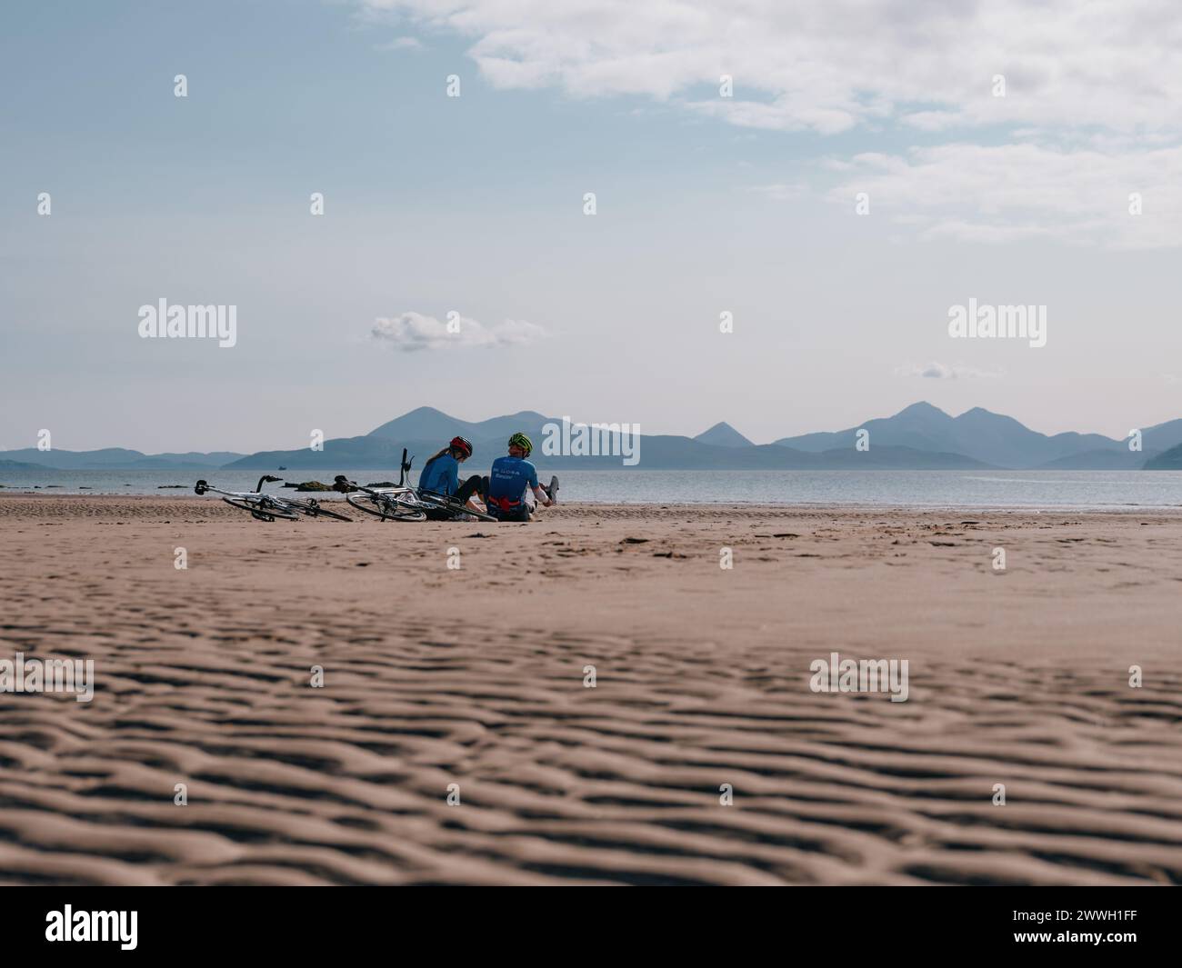 Touring cyclist couple enjoying Applecross Sands beach in the summer ...