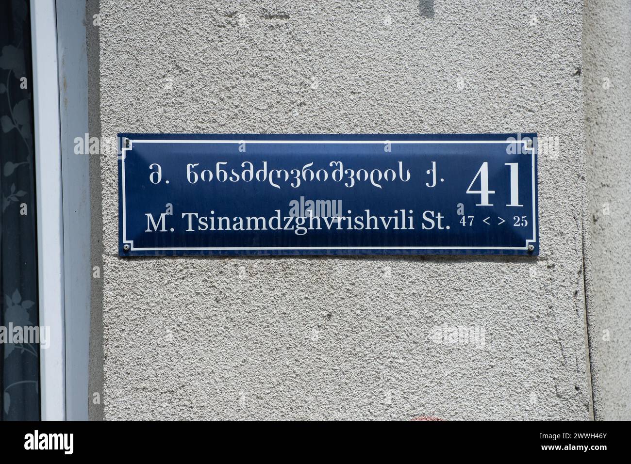 Street sign and name in Georgian and transliterated English, mounted to ...