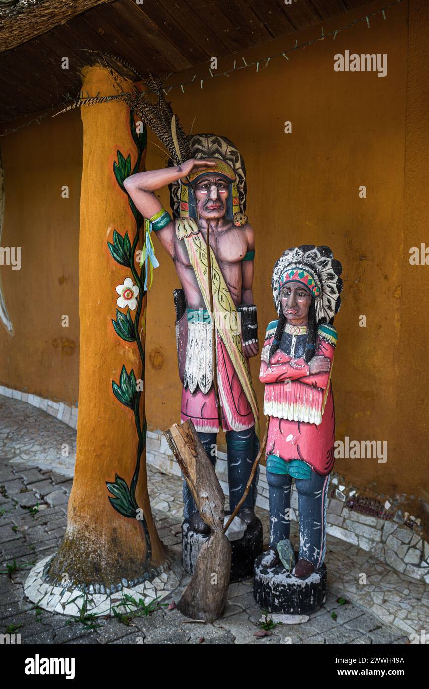 A wooden sculpture of two native indians in their costume. They stand ...