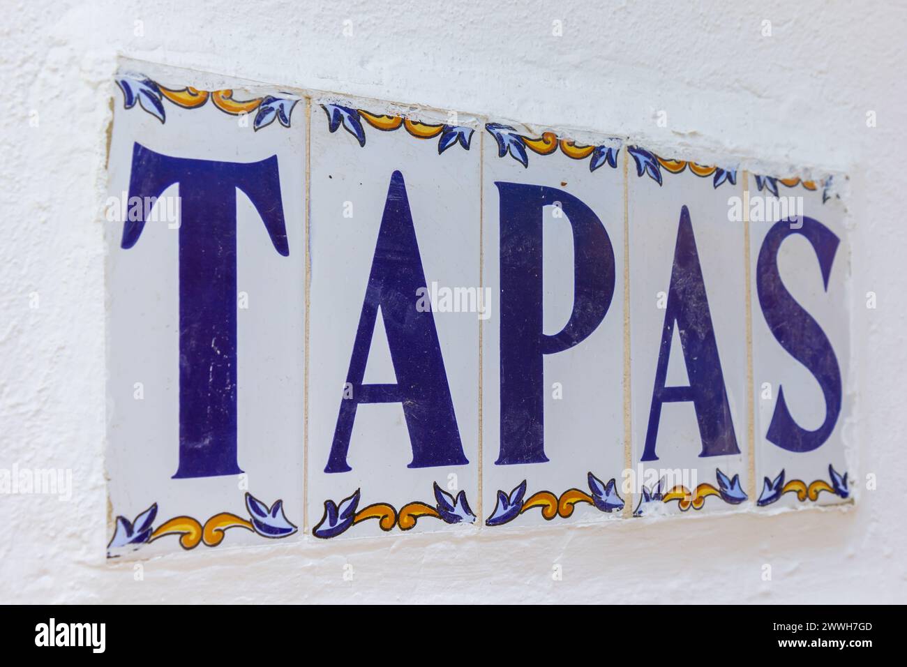 Tiled sign with the word Tapas in blue letters Stock Photo - Alamy