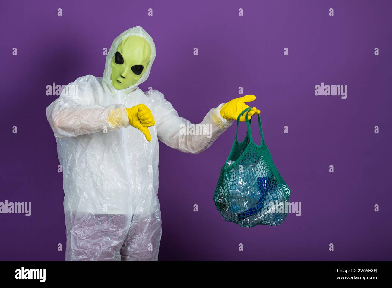 An individual in an alien costume gives a thumbs down to plastic waste ...