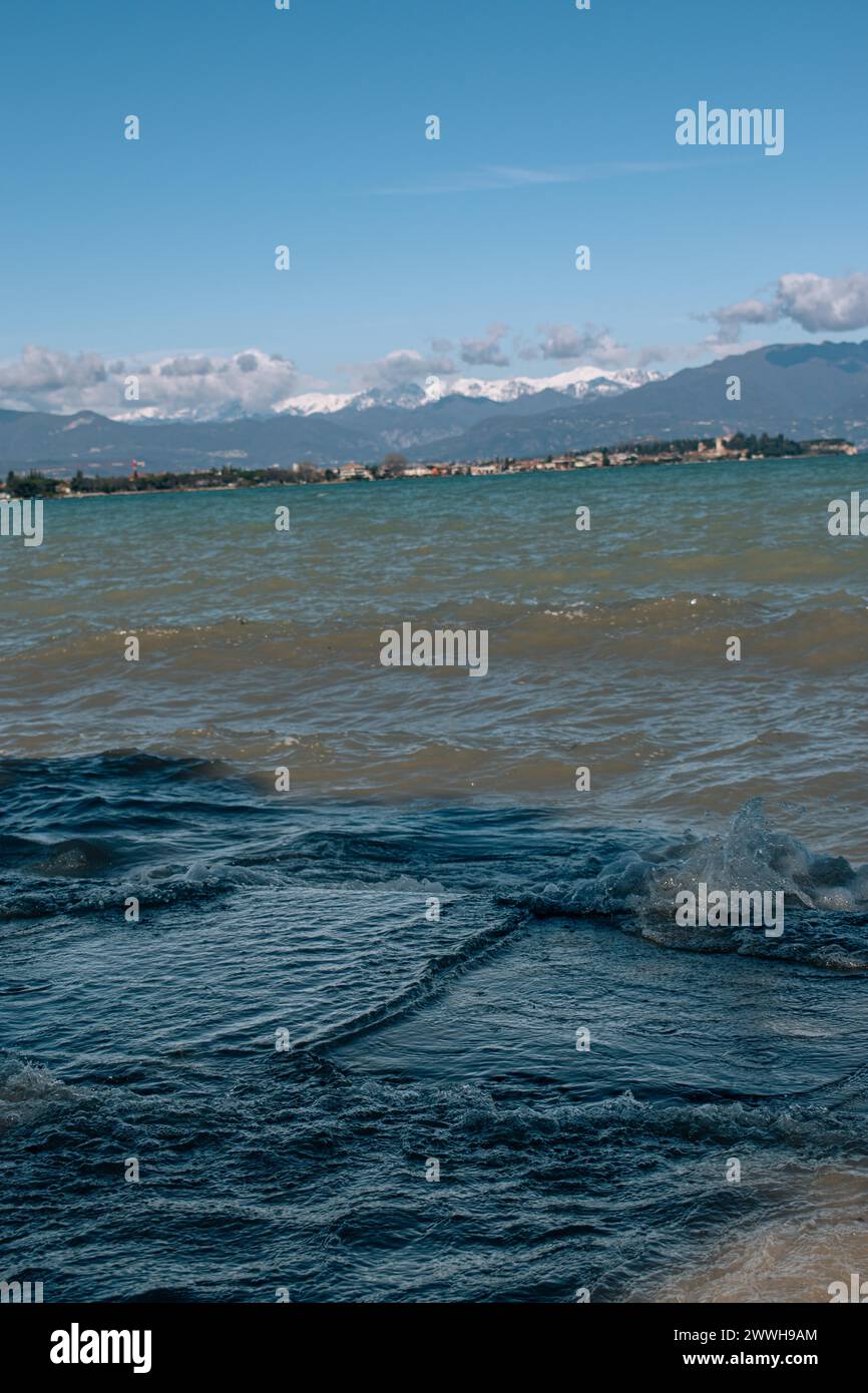 View over the wavy Lake Garda under a blue sky with clouds, Sirmione ...