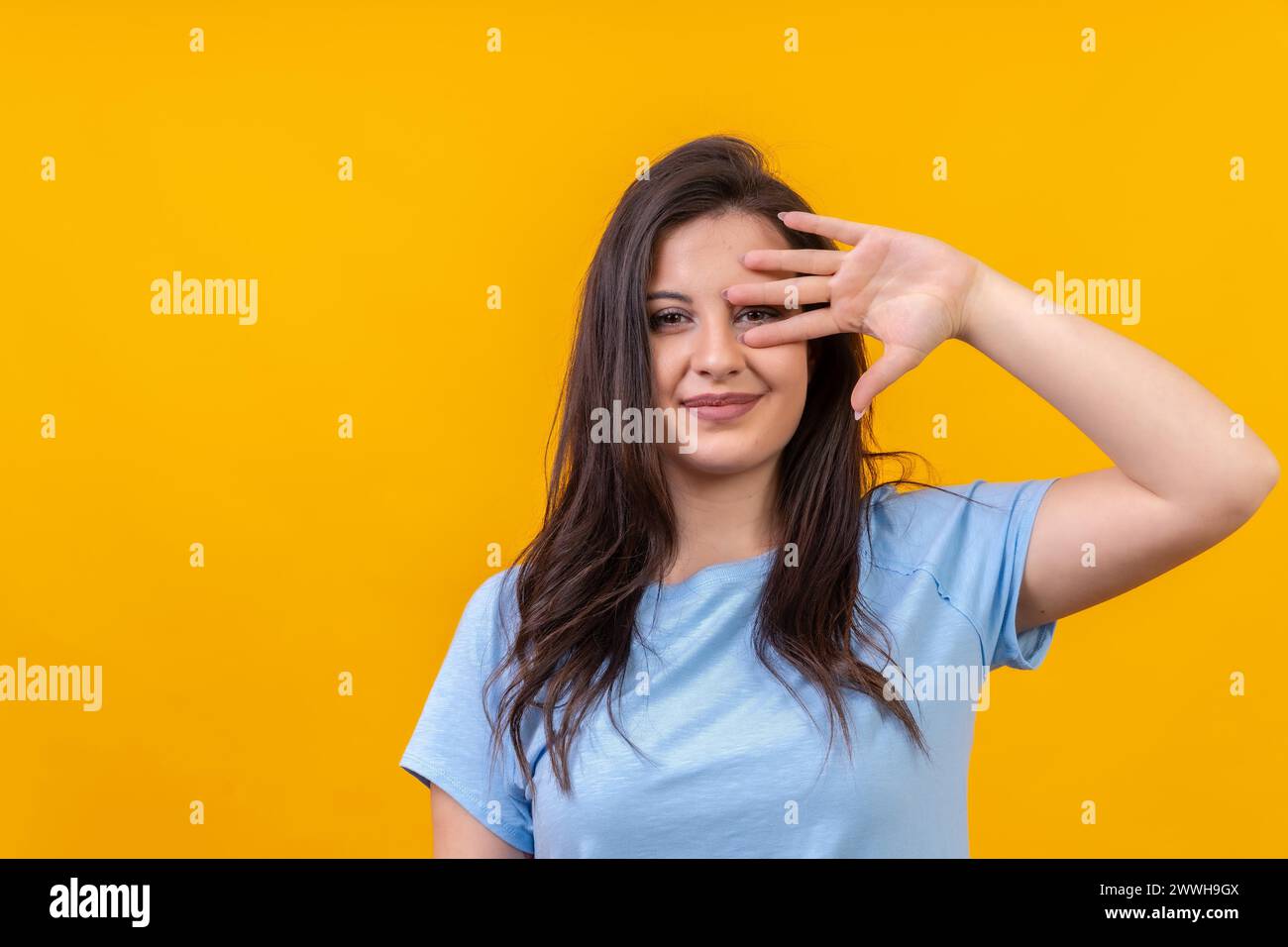 Studio portrait with yellow background of a caucasian woman hiding on ...