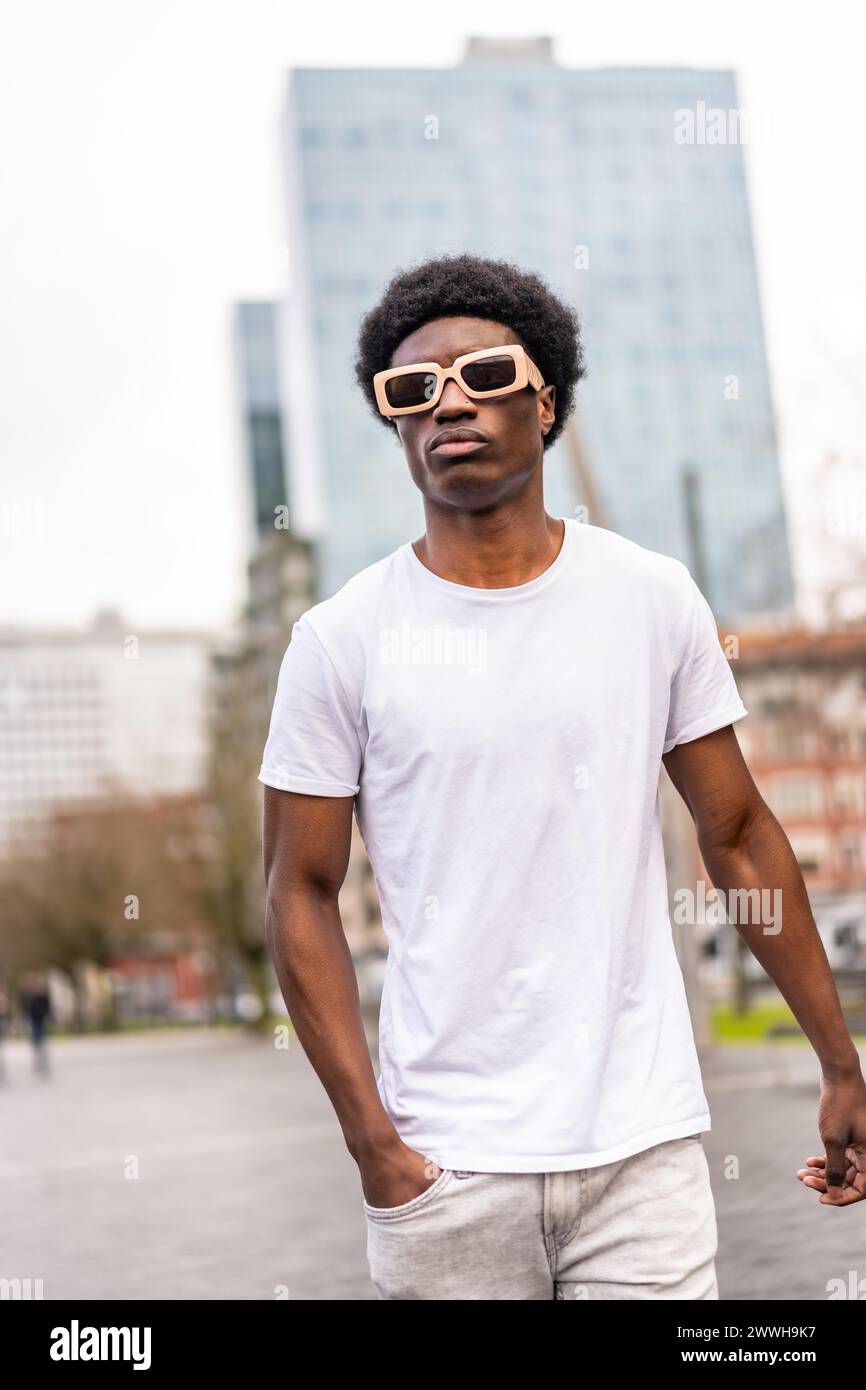 Vertical photo of a confident young african man walking in the city ...