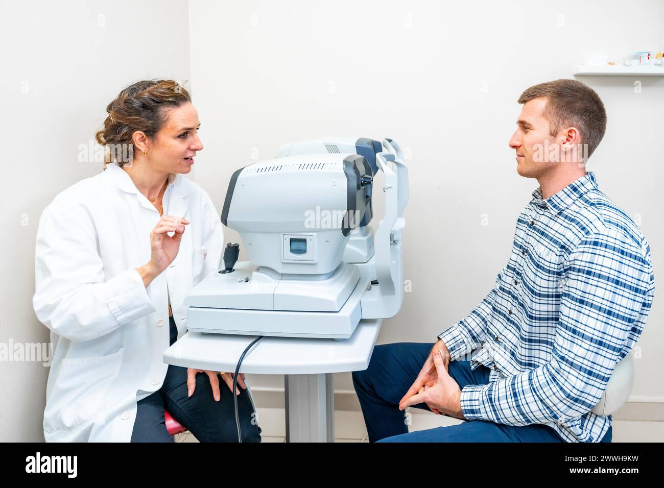 Female ophthalmologist explaining the procedure of a scan to a patient ...