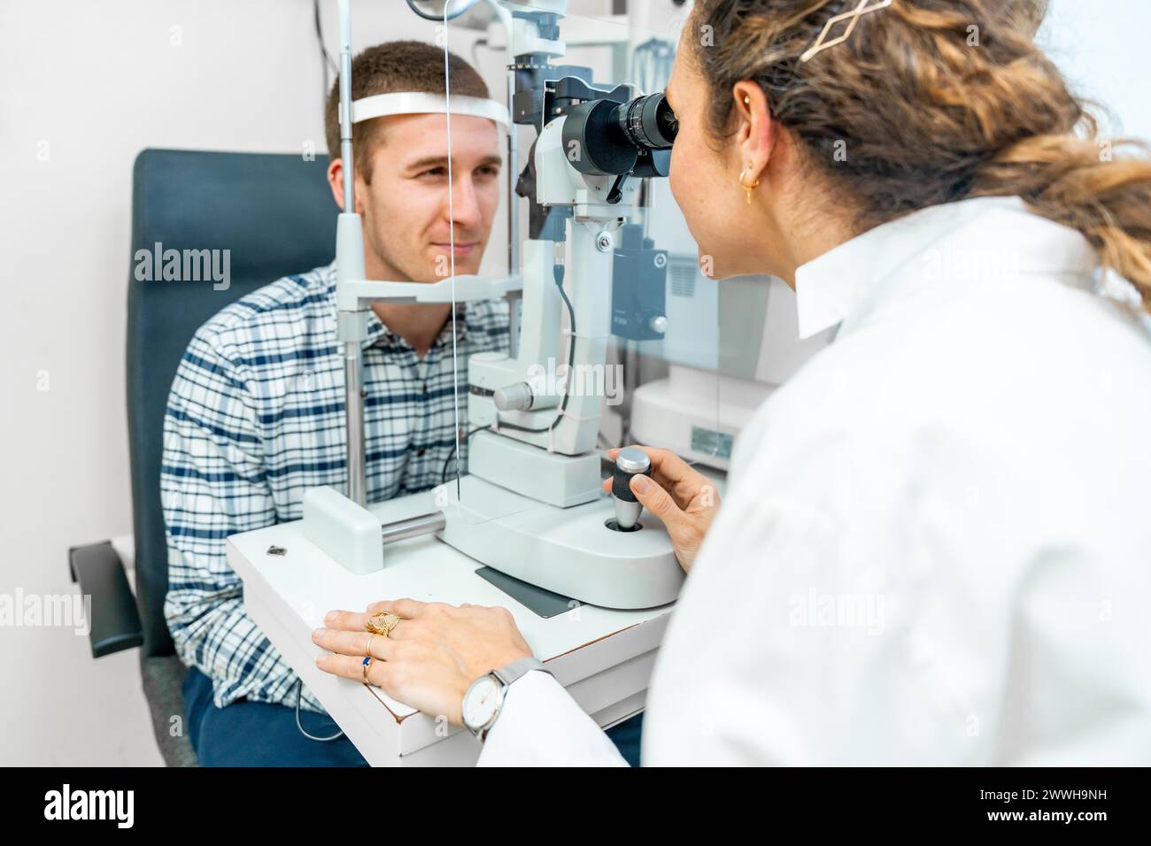 Smiling man checking the eye in an annual check up in the ...