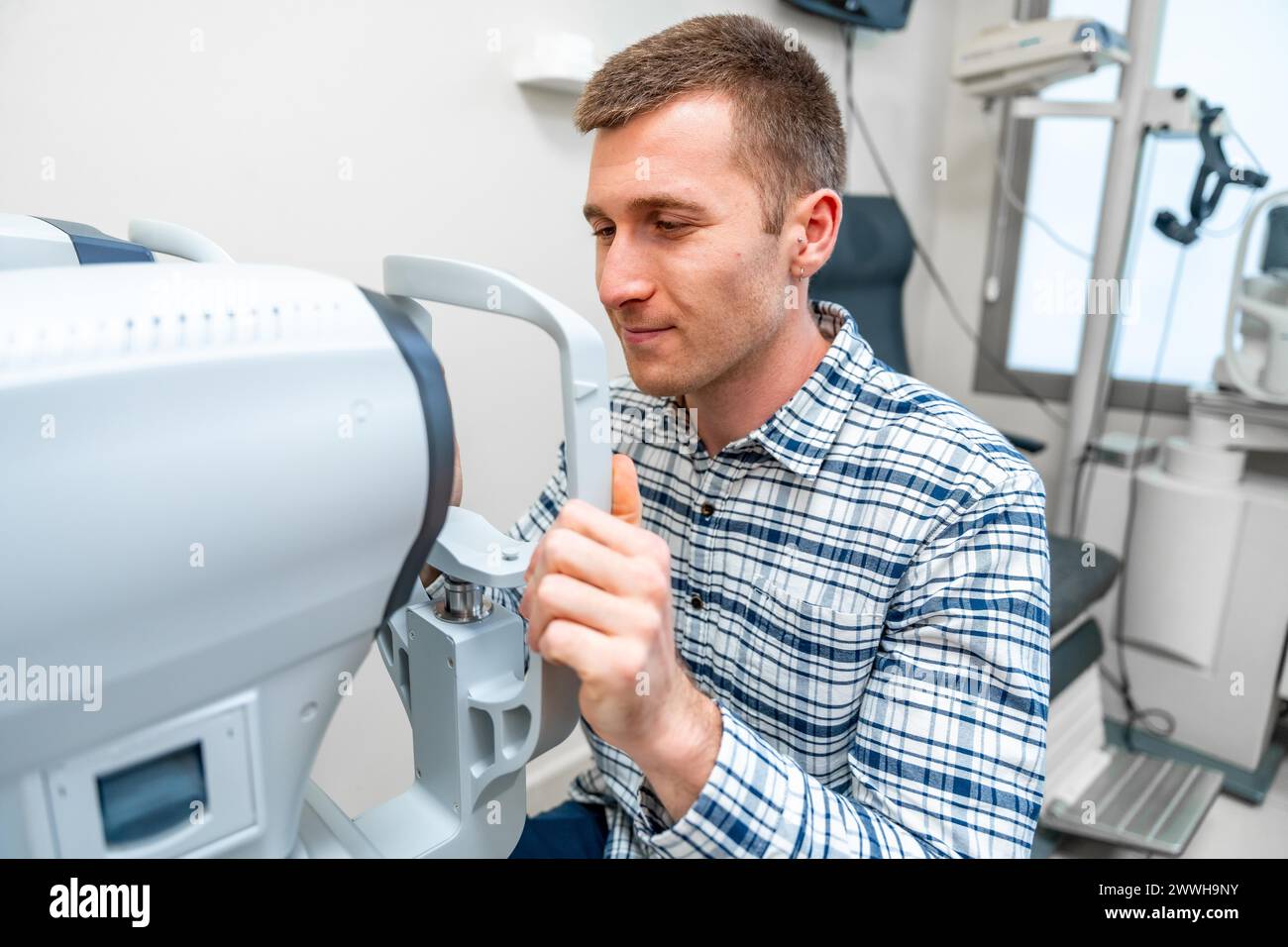 Man holding the handles of a eye scanner in an ophthalmology clinic ...