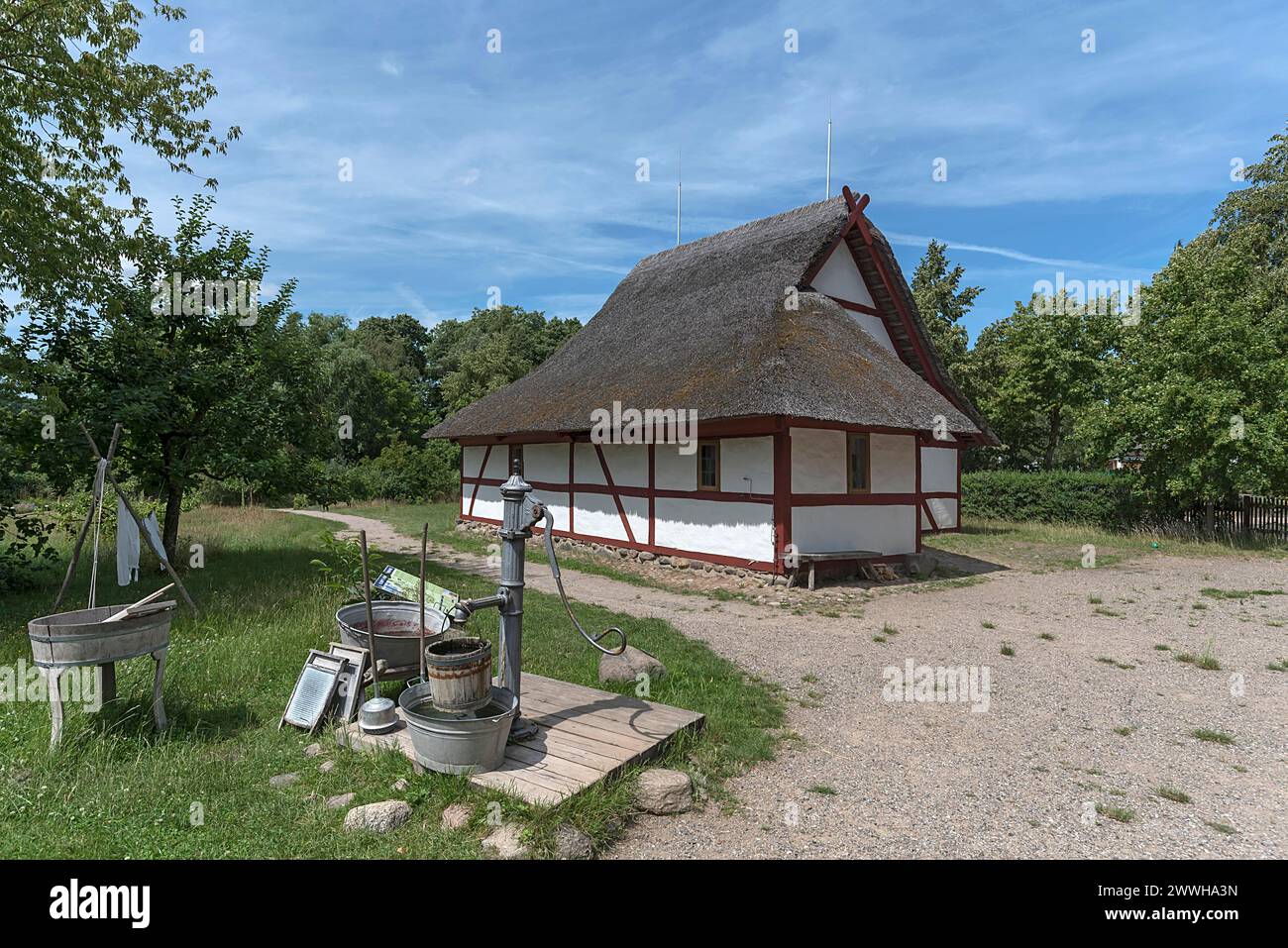 Thatched half-timbered barn, in front a water pump with washing tubs ...
