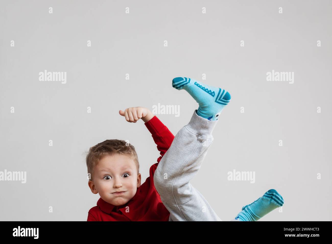 A young boy is balancing on his back with his legs and hands up in the ...