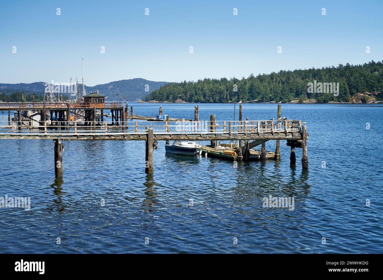 The Rotary pier, Sooke Harbour, surrounded by blue water, hills and ...