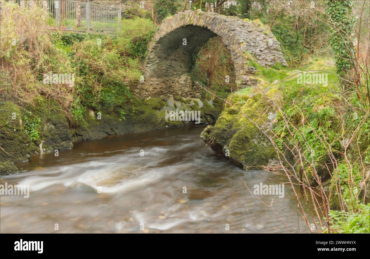 Ancient arched Cromwell bridge over a fast flowing river in the early ...