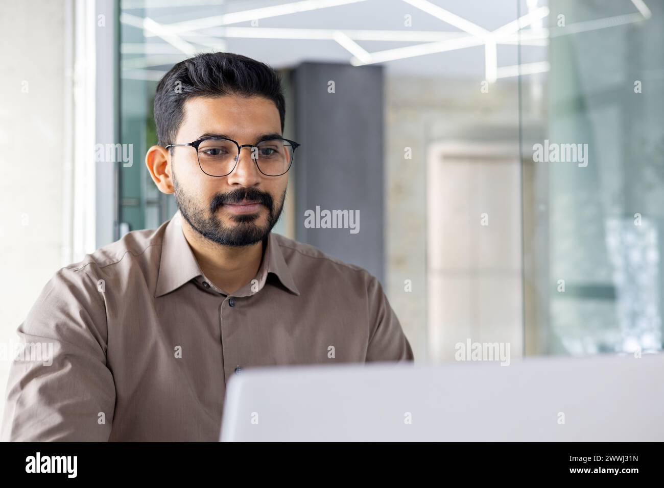 Focused Indian businessman using a laptop at his office workspace ...