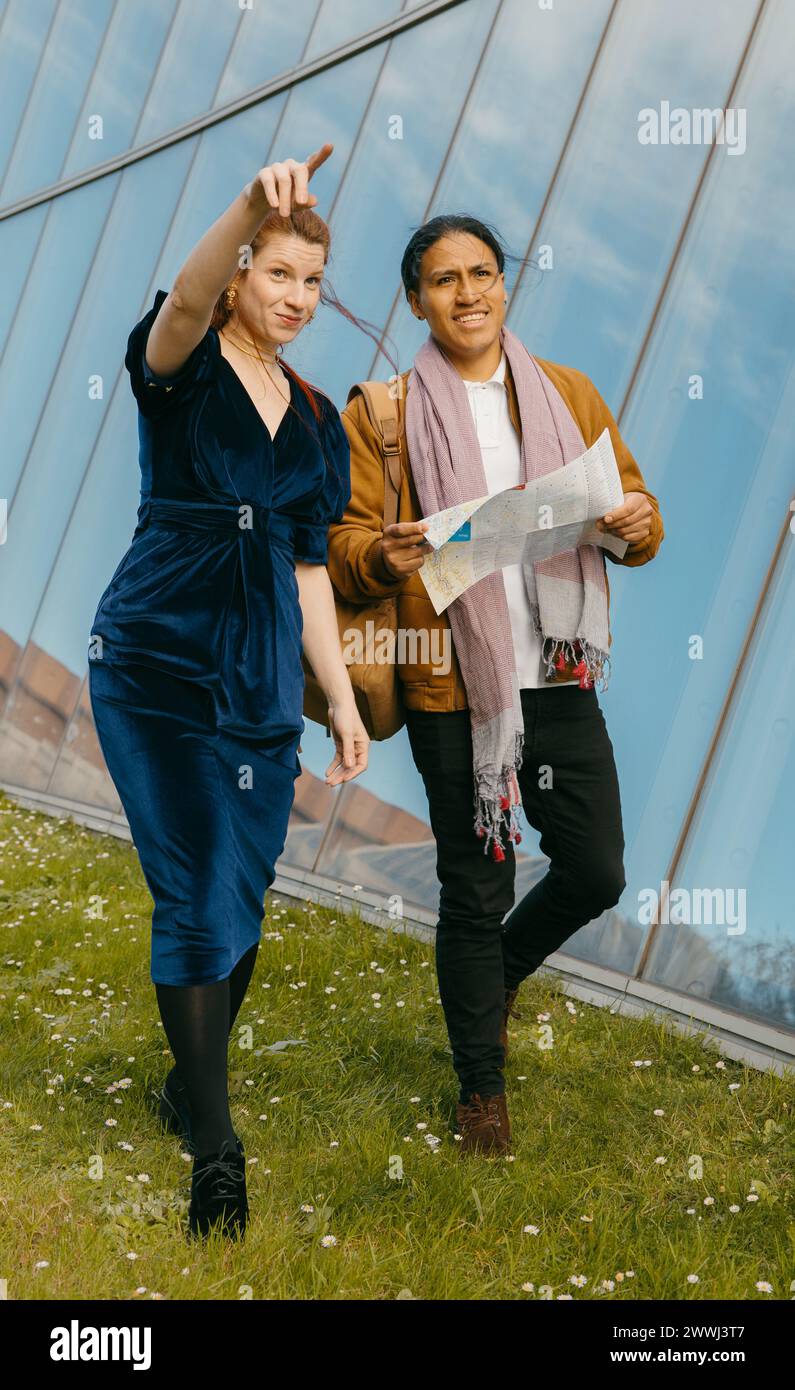 Joyful travel partners with a map, the woman pointing excitedly towards ...