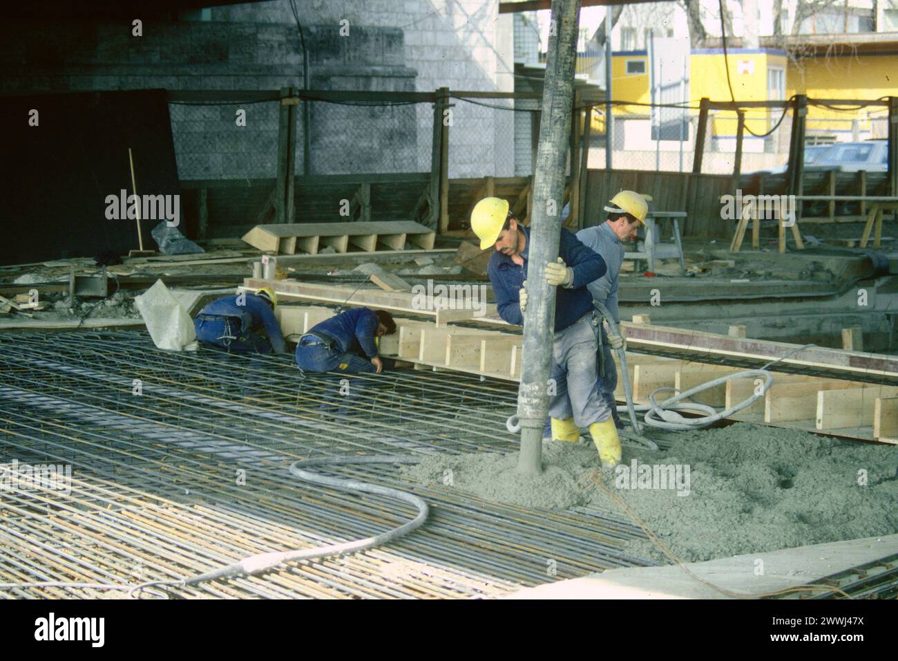 Workers piping concrete into foundations during construction of road ...