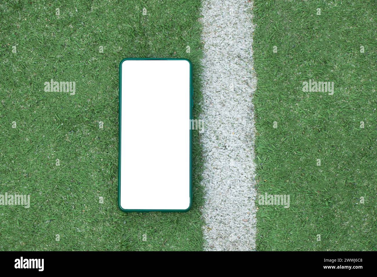 A phone with a white screen lies on a football field near a white ...
