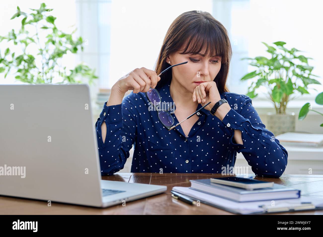 Tired sad mature woman at workplace at table with computer laptop Stock ...