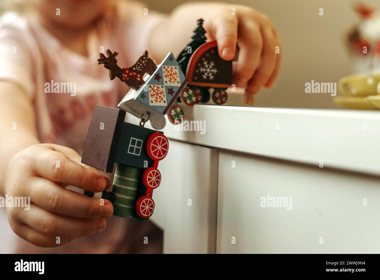 A child happily playing with a colorful toy train set, pushing the ...