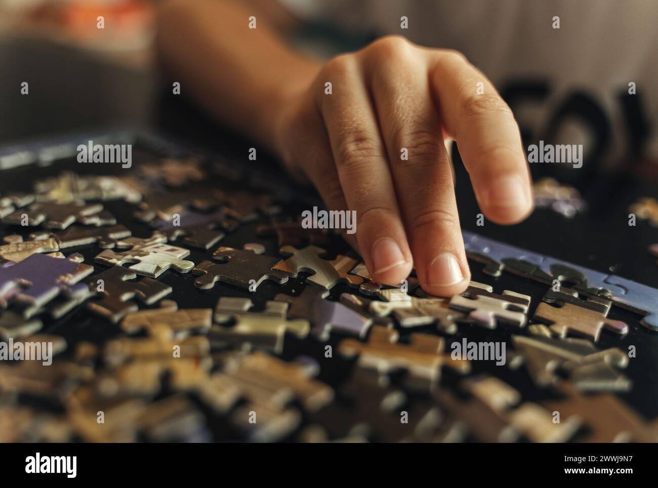 A person is concentrating on placing a puzzle piece into the correct ...