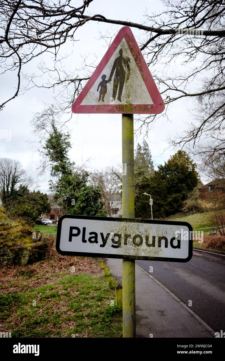 A playground sign with graphic and words covered in moss giving an ...