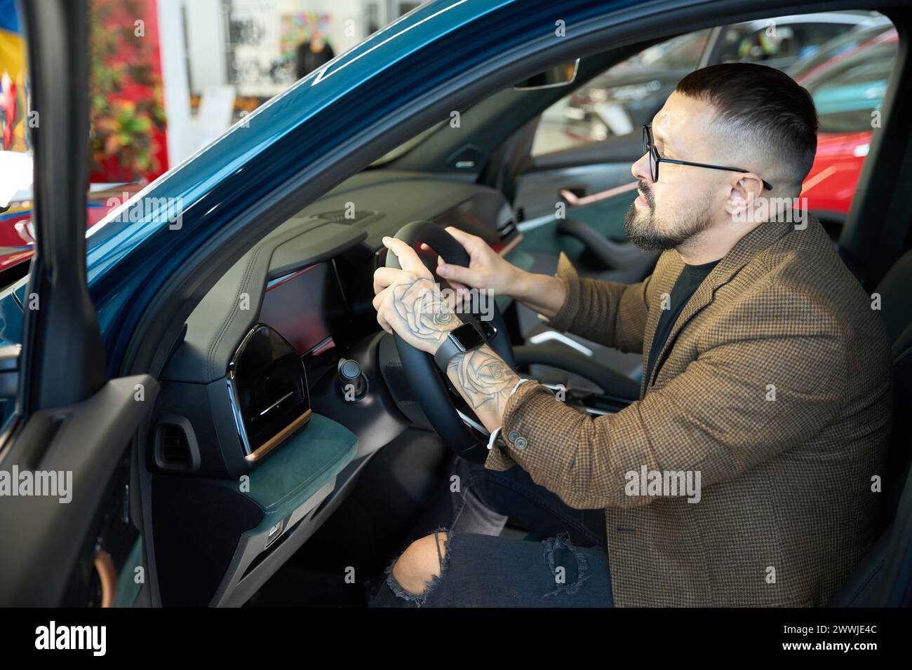 Guy in a car store sits behind the wheel Stock Photo - Alamy