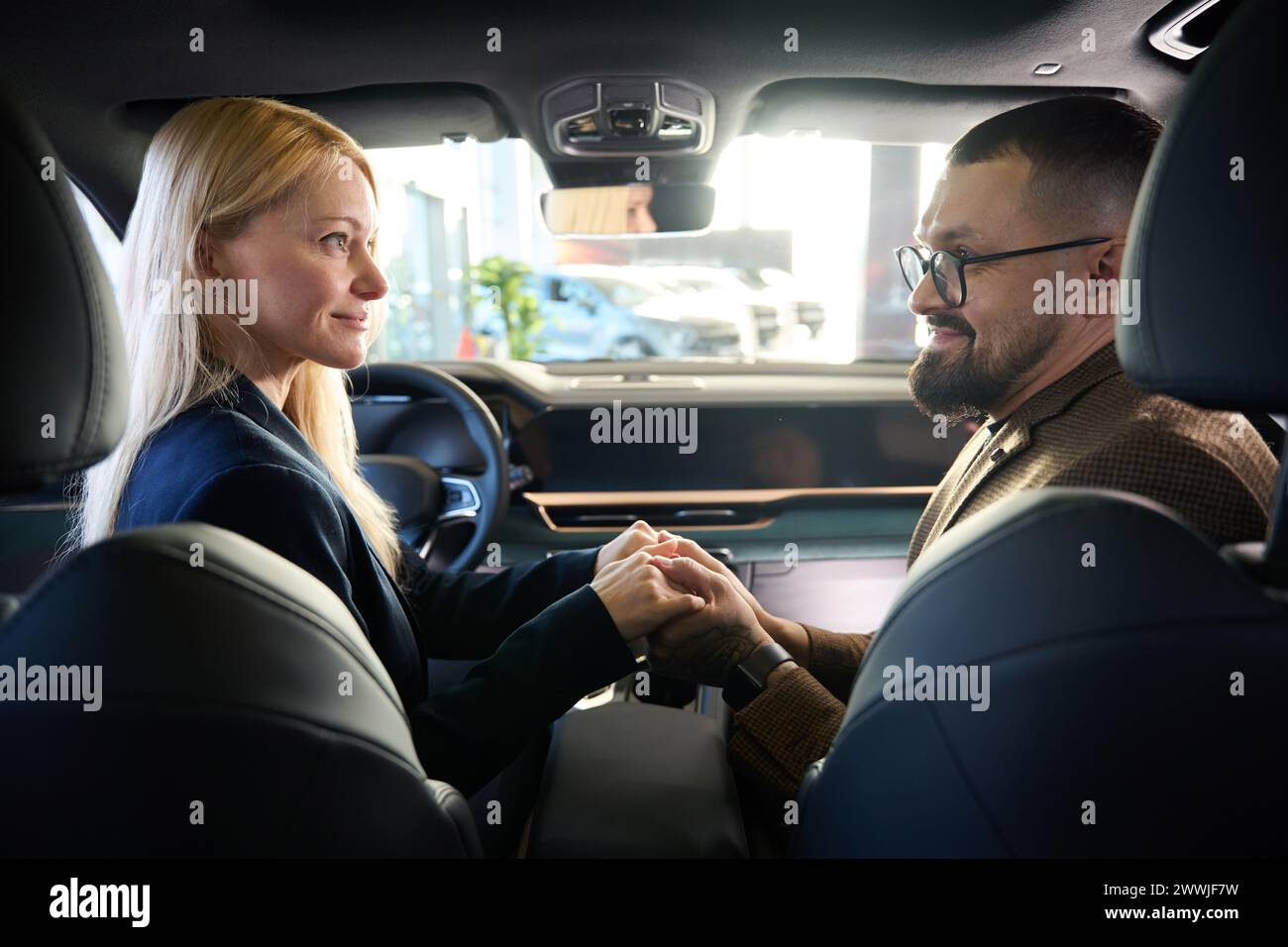 Young couple holding each other hands in the car Stock Photo - Alamy