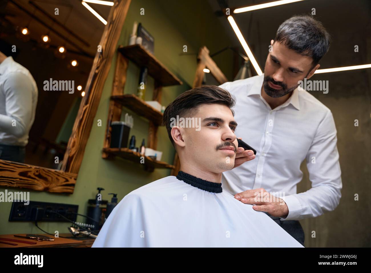 Barber using hair clipper for making stylish hairstyle Stock Photo - Alamy